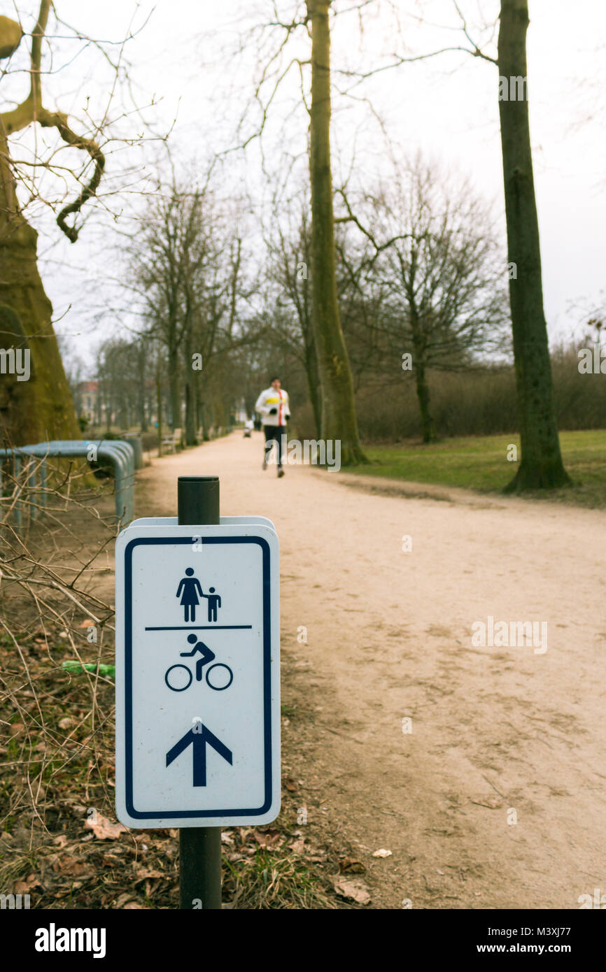 Sign indicating direction of bicycle and walking path in a park with ...