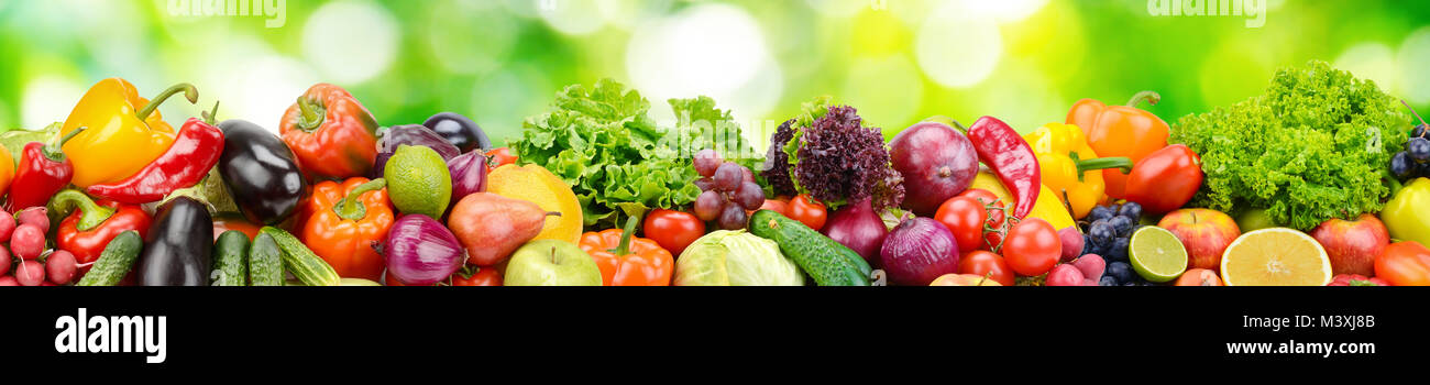 Panorama of fresh vegetables and fruits on natural blurred background ...