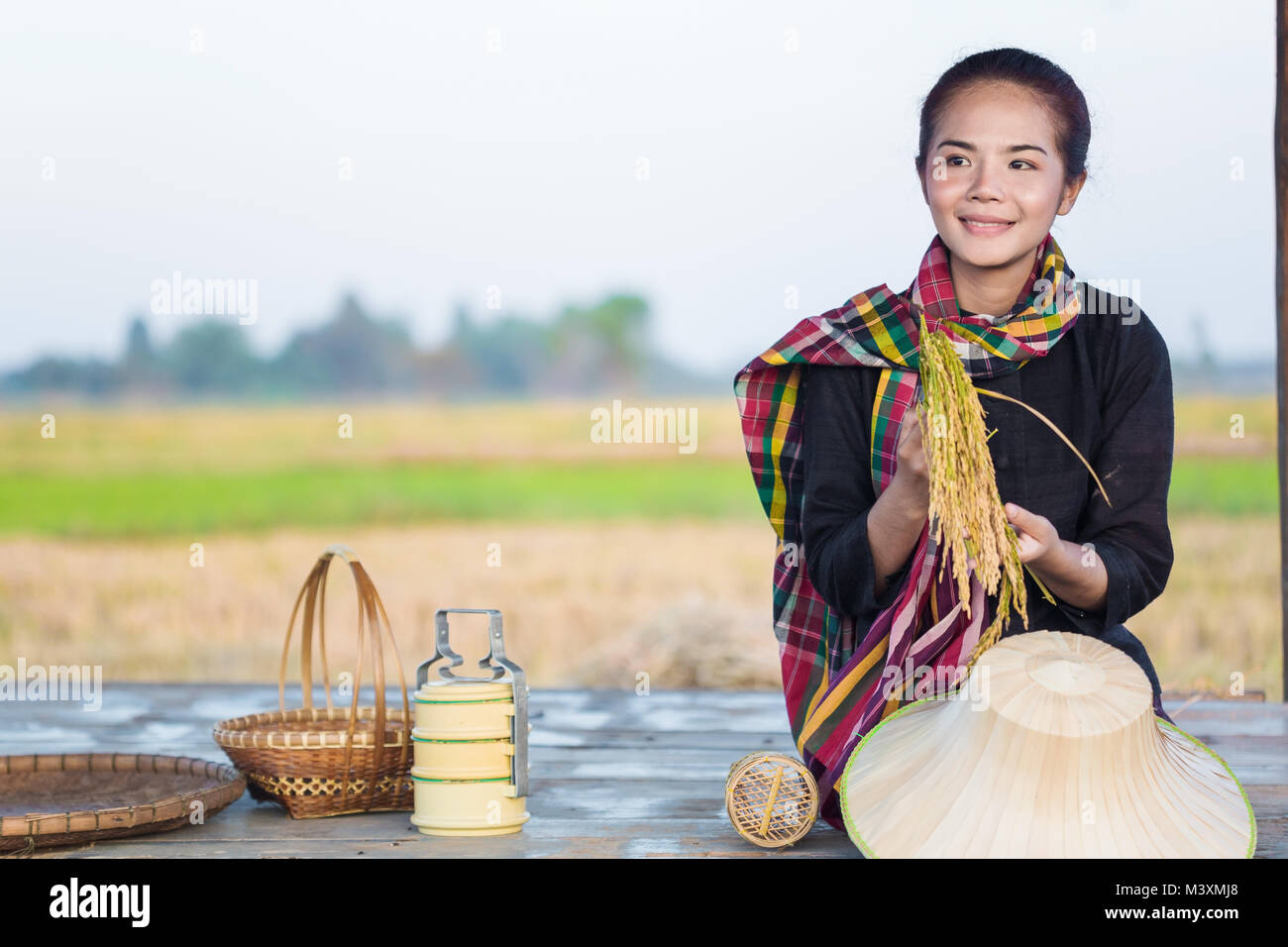 farmer woman holding rice and sitting in cottage at rice field ...