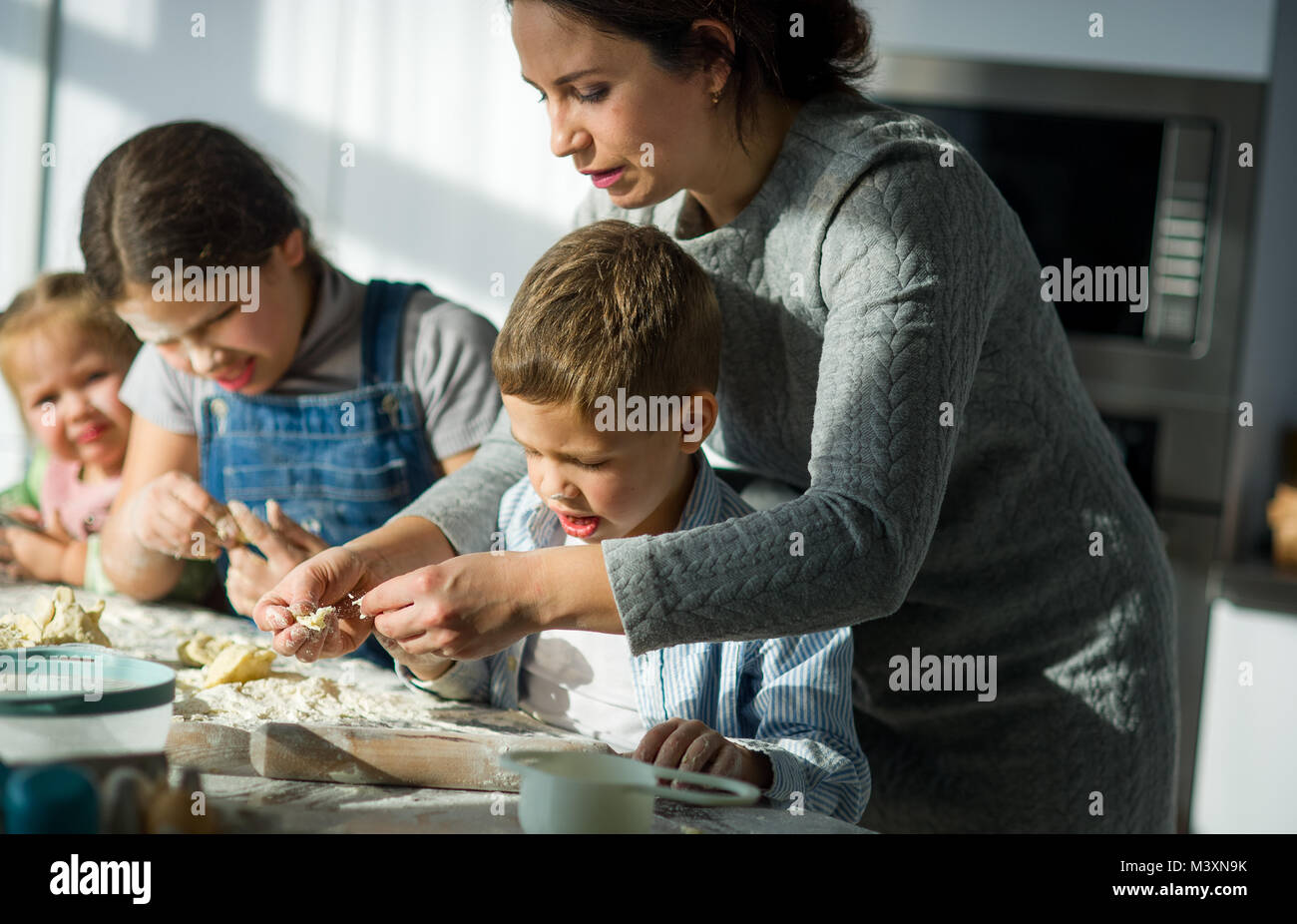 Mother and three children prepare something from the dough. Children ...