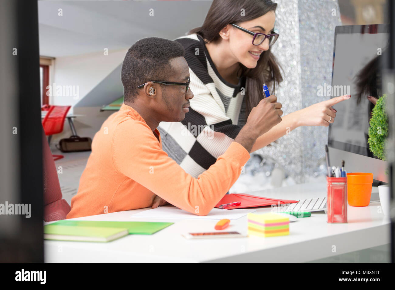 Two diverse work colleagues smiling and writing down notes while ...