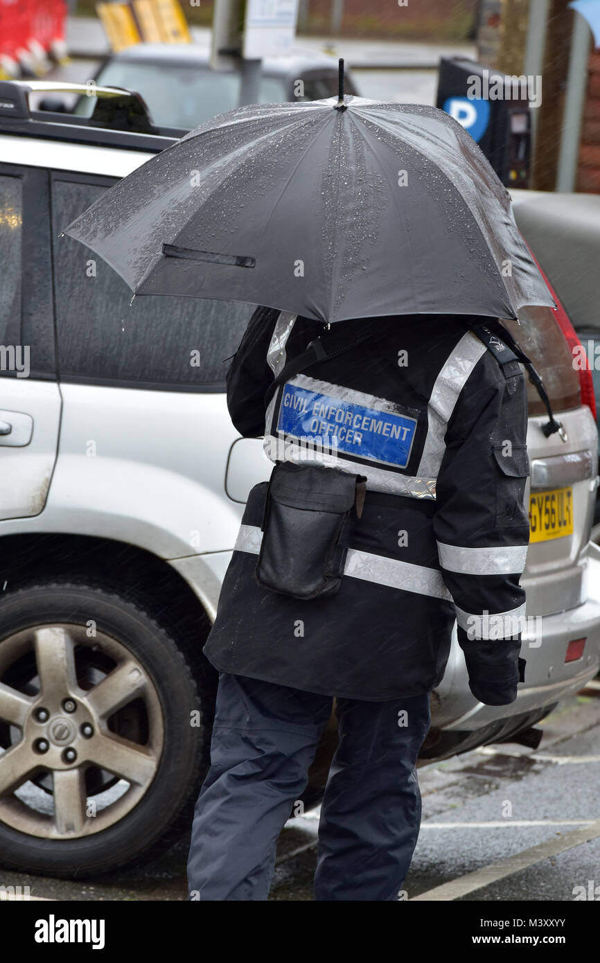 A traffic warden or civil enforcement office in a rain storm or ...