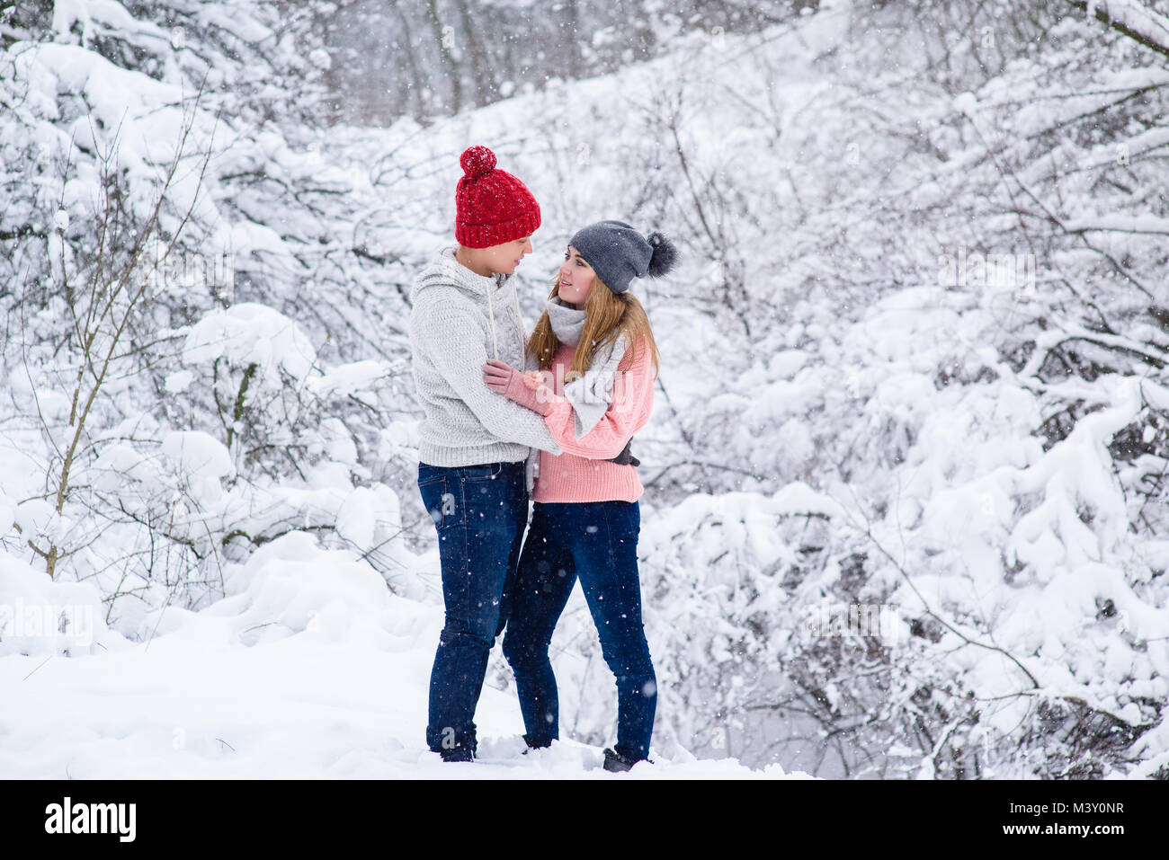 Snowflakes around woman and man in love full-length in winter forest ...