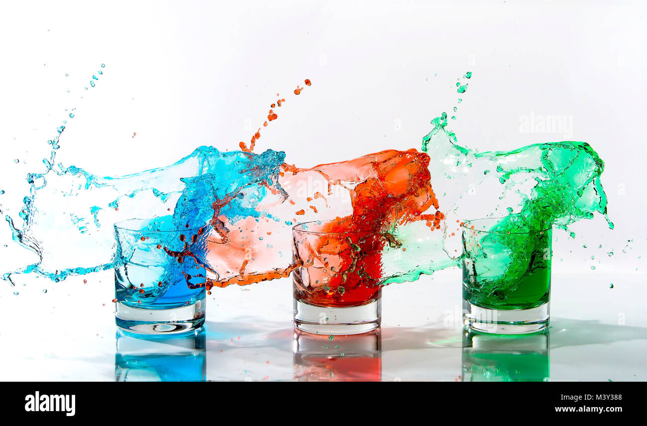 Coloured drinks splashing up from three glasses in similar patterns Stock Photo - Alamy