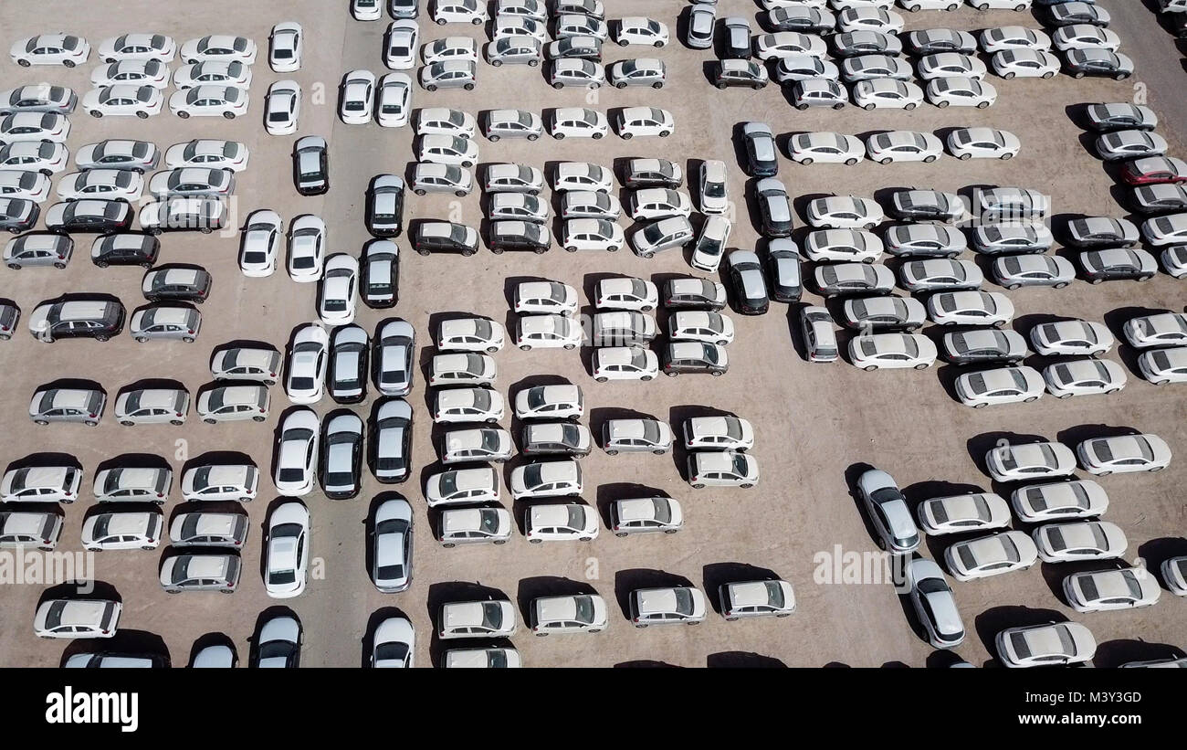 New cars covered in protective white sheets parked in a holding ...