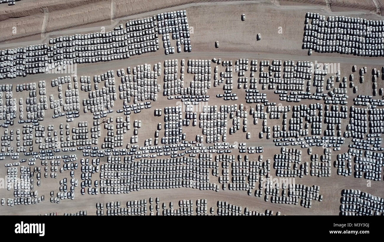 New cars covered in protective white sheets parked in a holding ...
