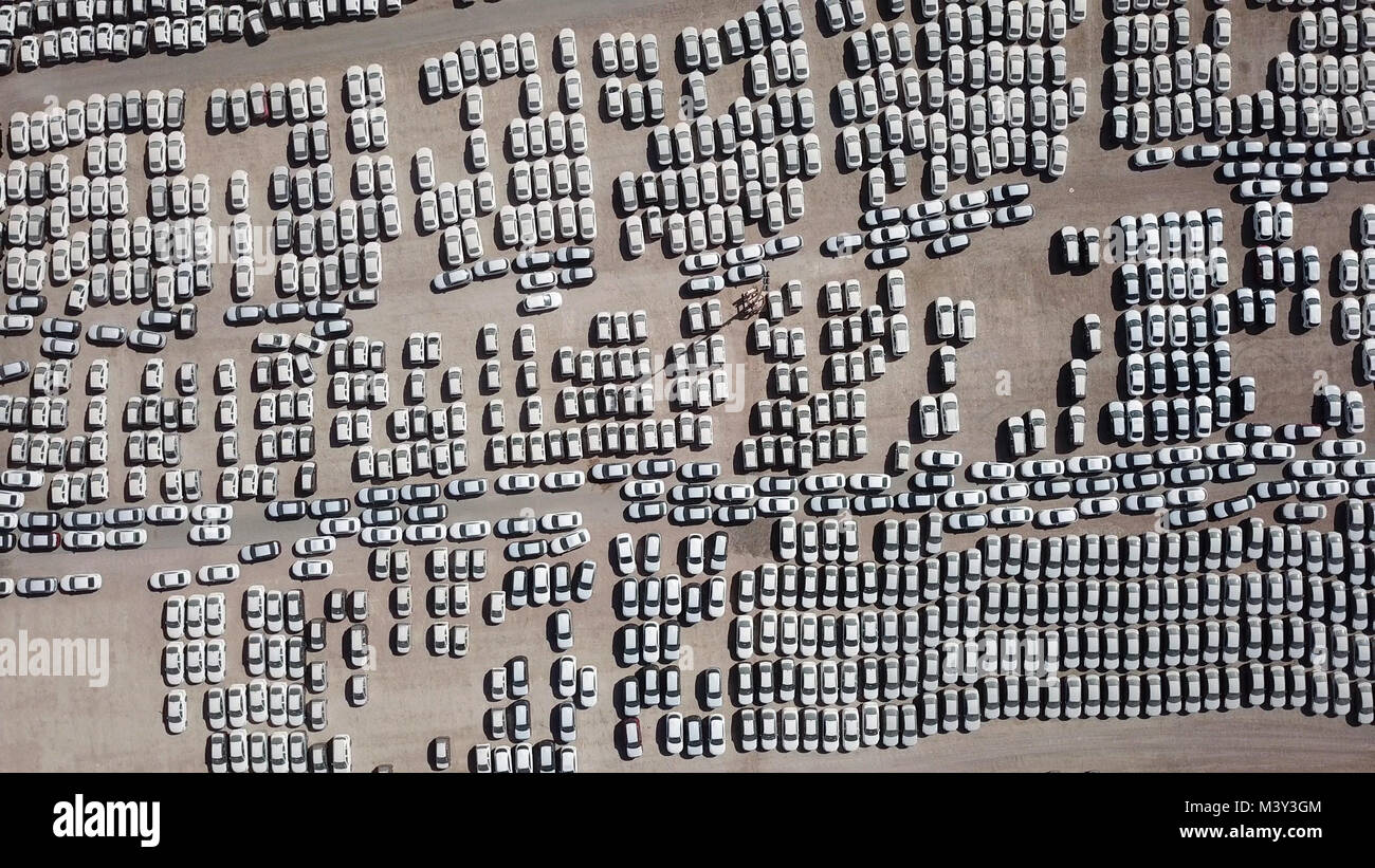 New cars covered in protective white sheets parked in a holding ...