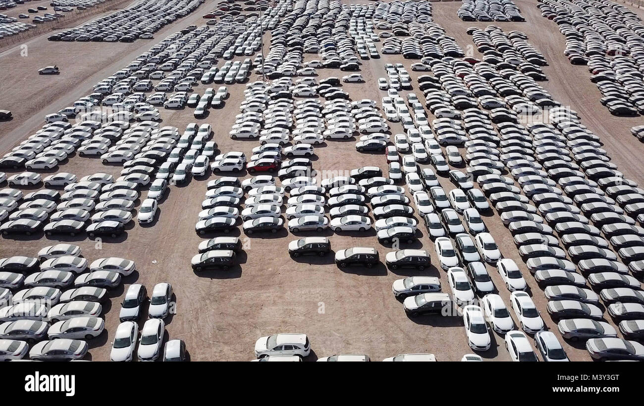 New cars covered in protective white sheets parked in a holding ...