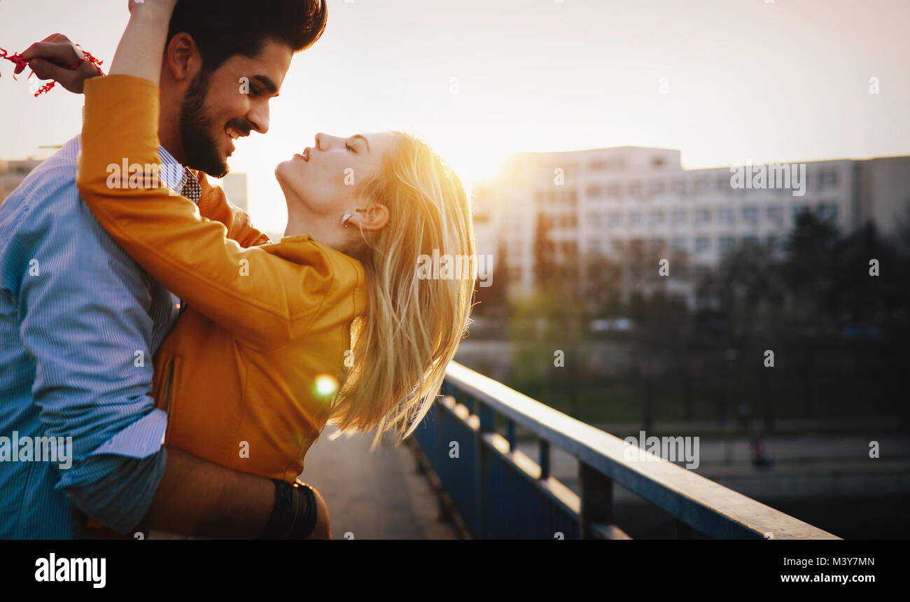 Couple in love cuddling while enjoying beautiful urban sunset together ...