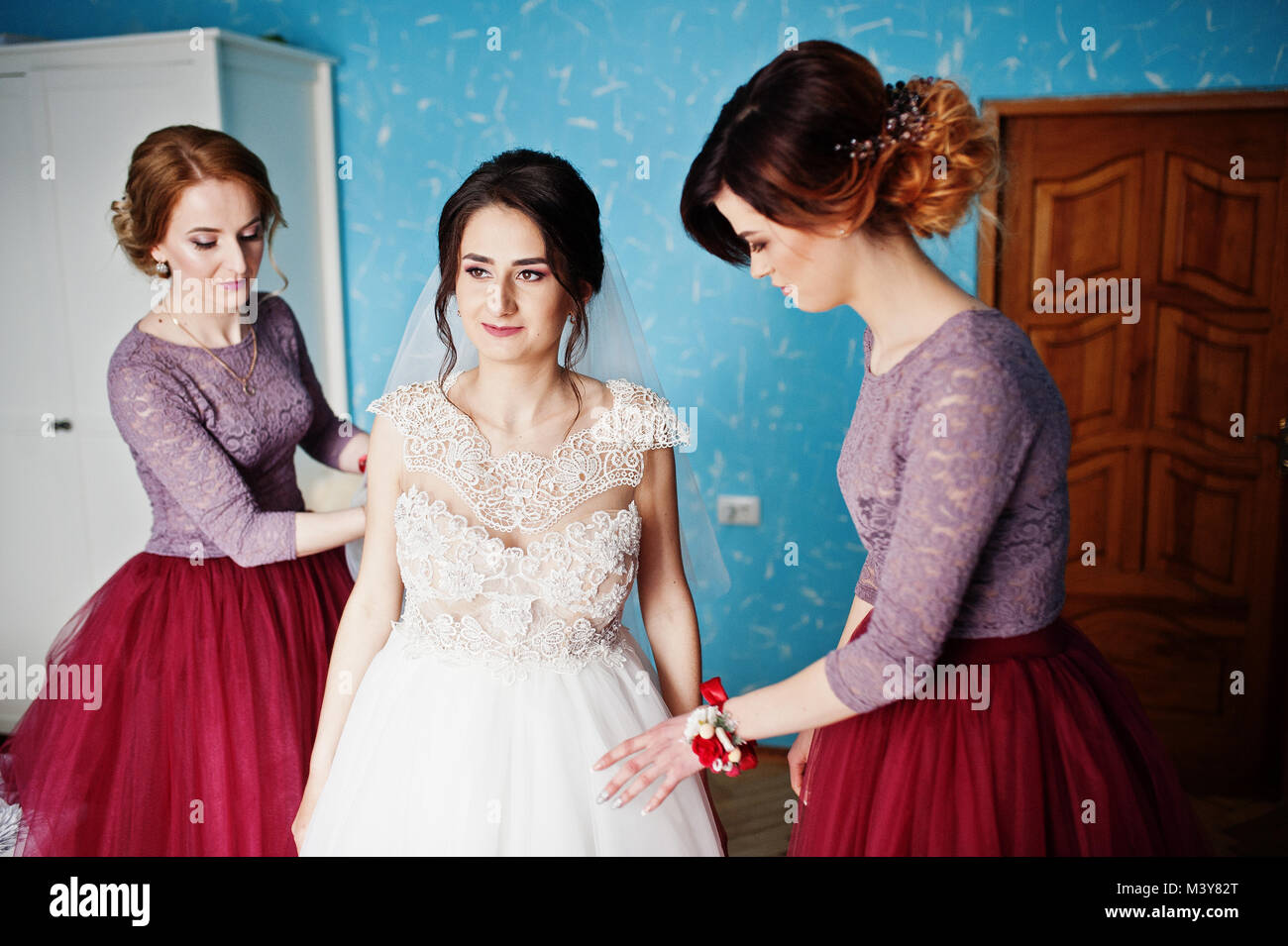 Bridesmaids helping bride to get ready for her wedding ceremony Stock ...