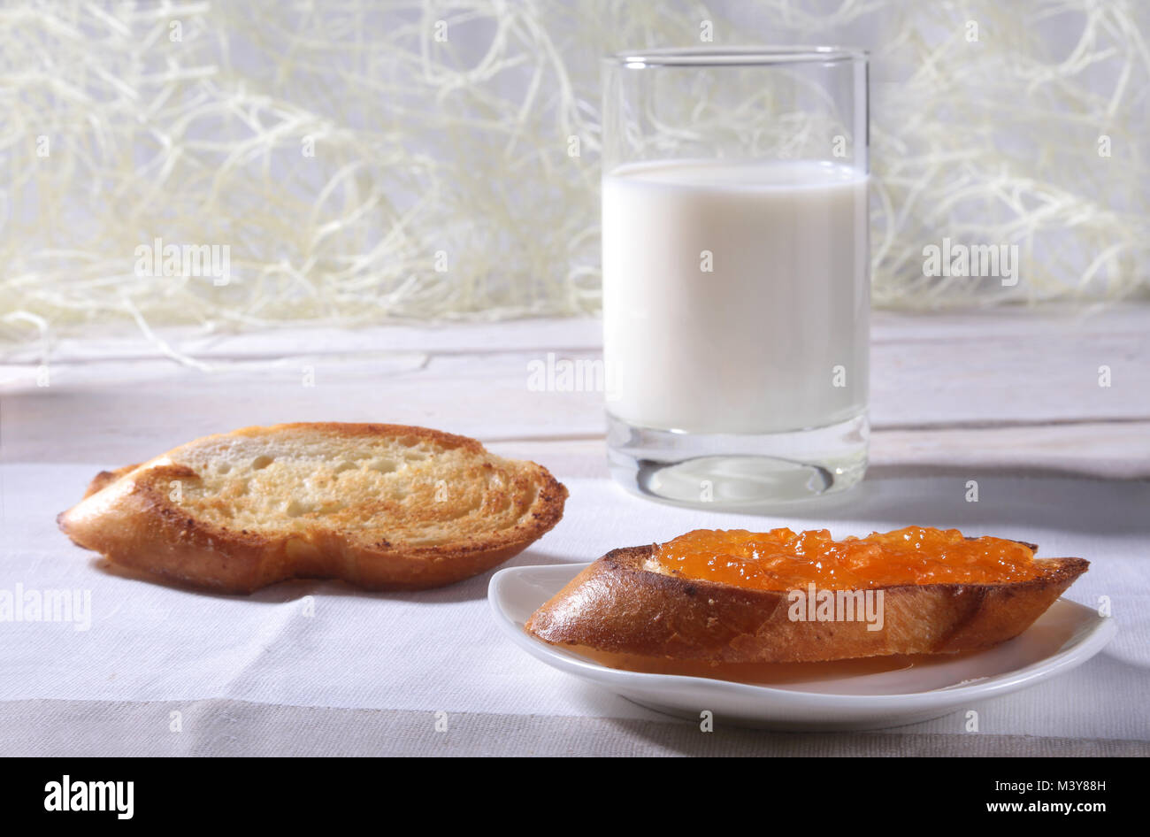 Morning Breakfast set with orange jam on bread toast and milk in glass ...