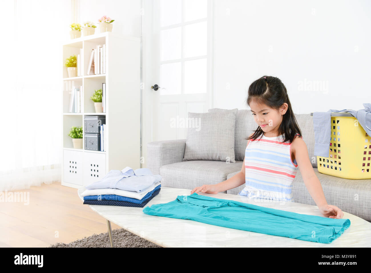 pretty beautiful female little kid children folding clothing in living ...
