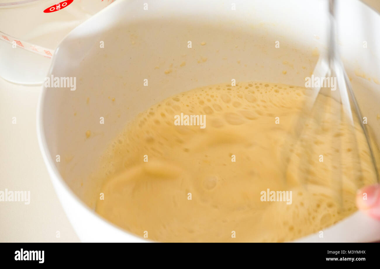 Beating mixture with whisk to make pancake batter for Shrove Tuesday ...