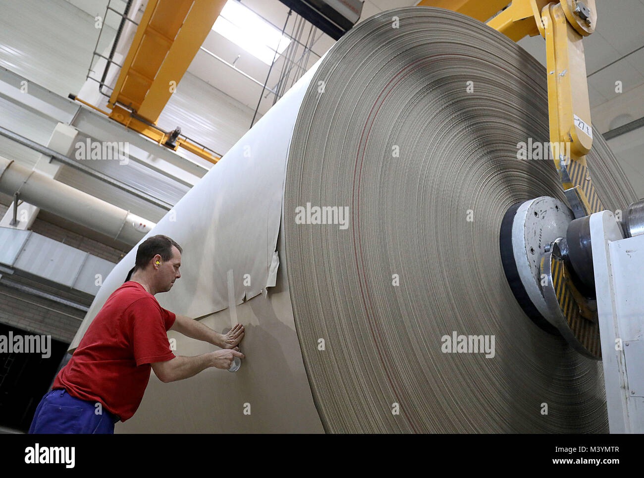 Dueren, Germany. 13th Feb, 2018. A worker tapes a roll of corrugated ...