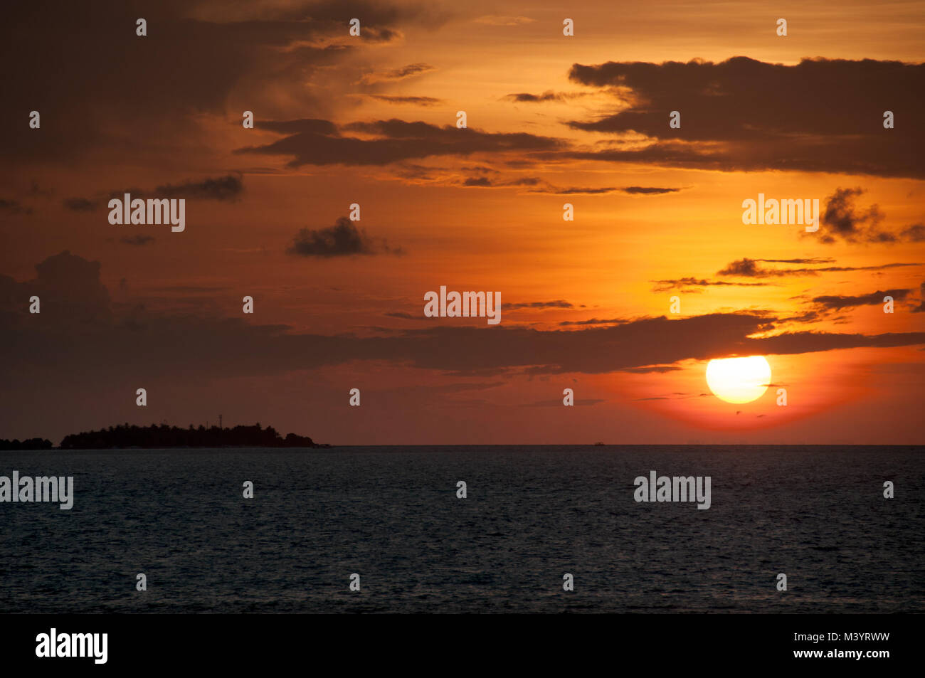 Bright fiery sunset on the ocean: a round ball of sun sets to the water ...
