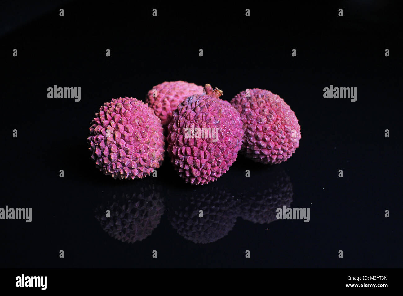Lychee or litchi litchies or lychees on black reflective studio ...