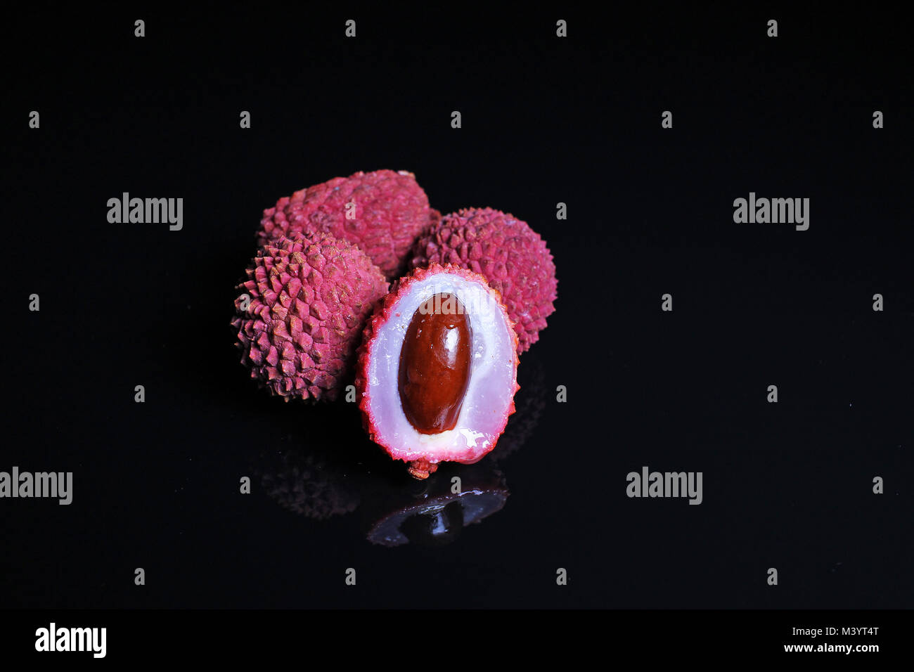 Lychee or litchi litchies or lychees on black reflective studio ...