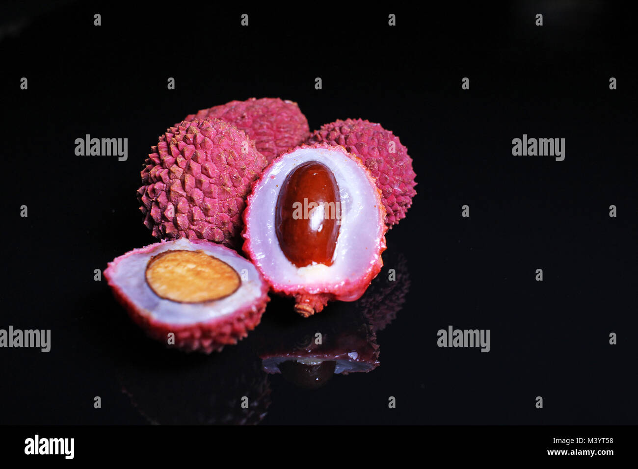 Lychee or litchi litchies or lychees on black reflective studio ...