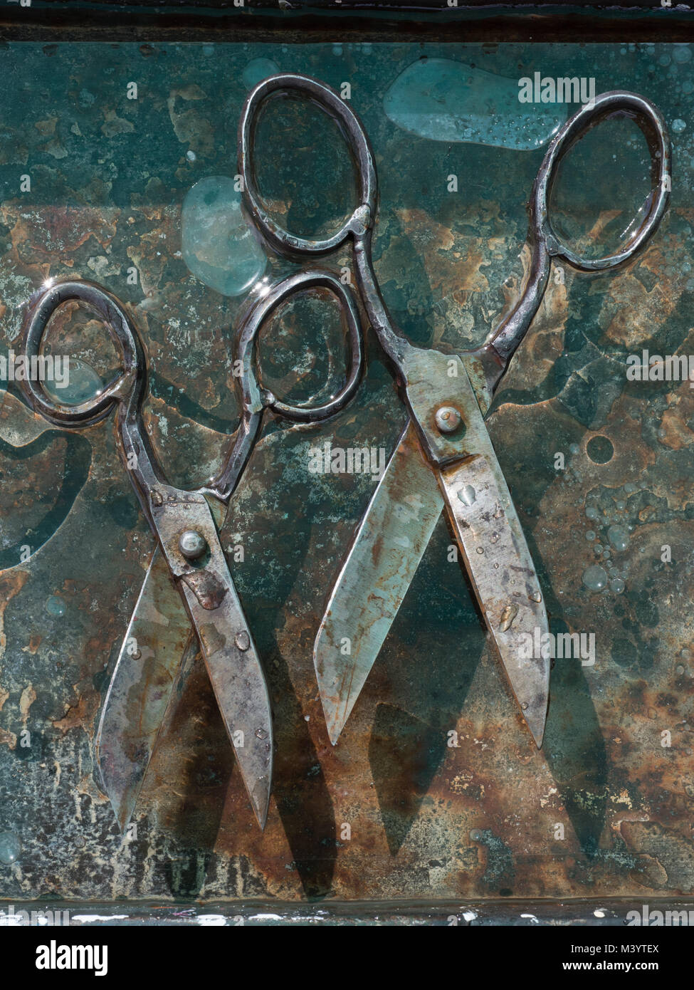 Two pairs of metal rusty old scissors, open, different size on an old ...