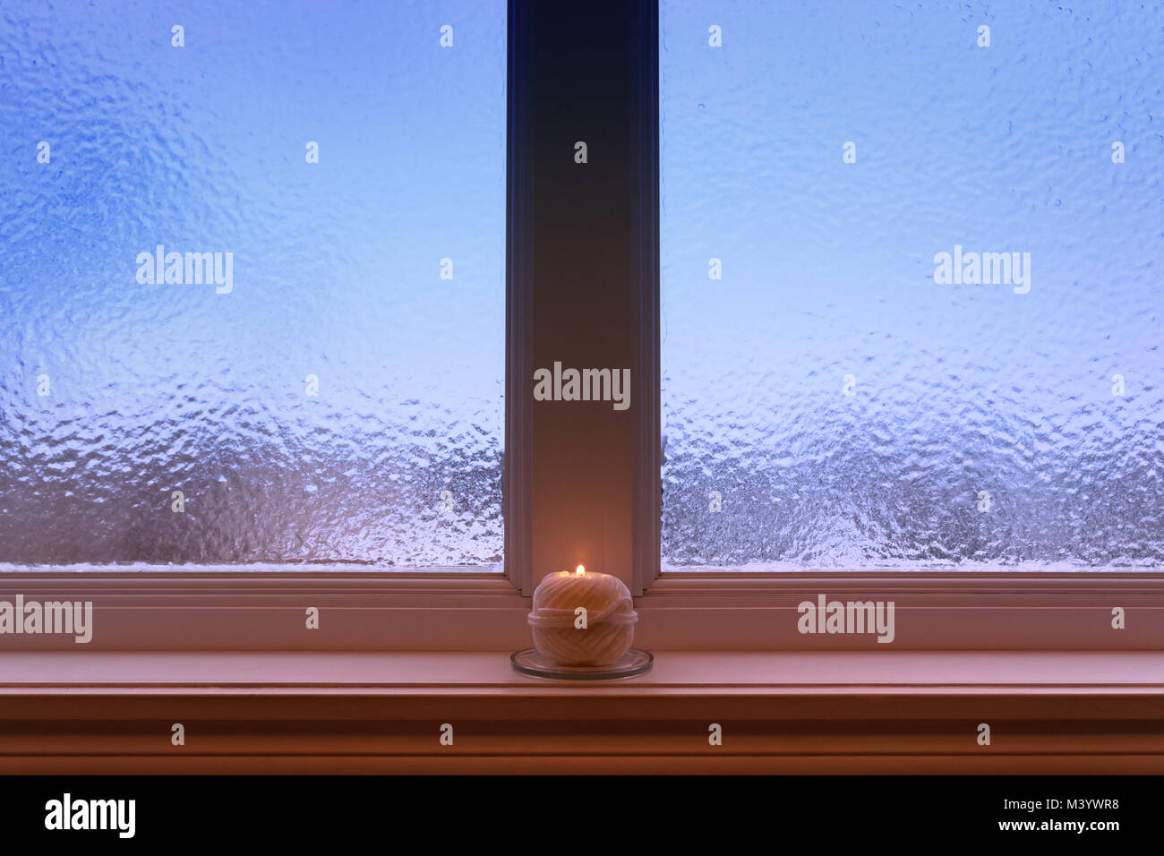 Frosted window, and ball of yarn candle on a windowsill Stock Photo - Alamy
