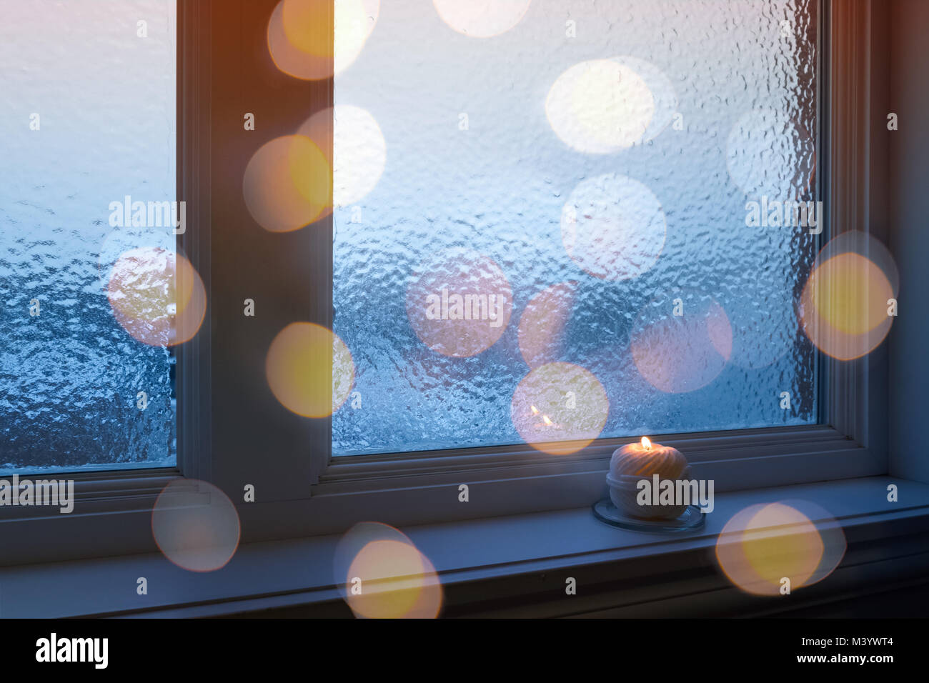 Frosted winter window, burning candle and golden bokeh lights Stock ...