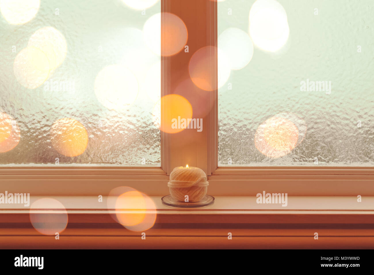 Frosted winter window and a cozy burning candle in golden light Stock ...