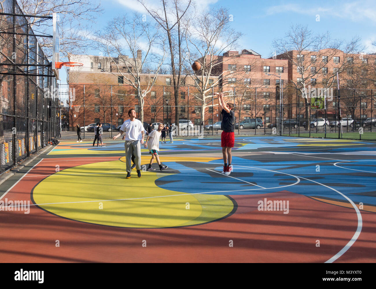 Young men playing basketball in a playground in New York's Lower East ...
