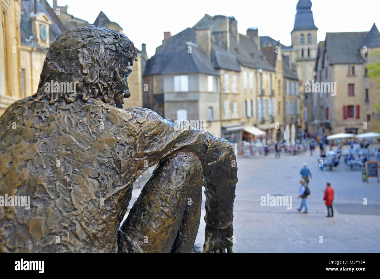 Bronze statue of a man looking out over the market square in an old ...
