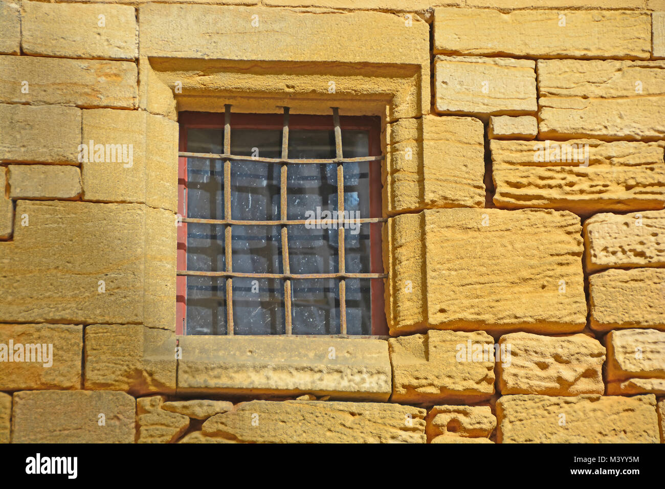 Medieval barred window in a dressed stone wall of golden stone Stock ...