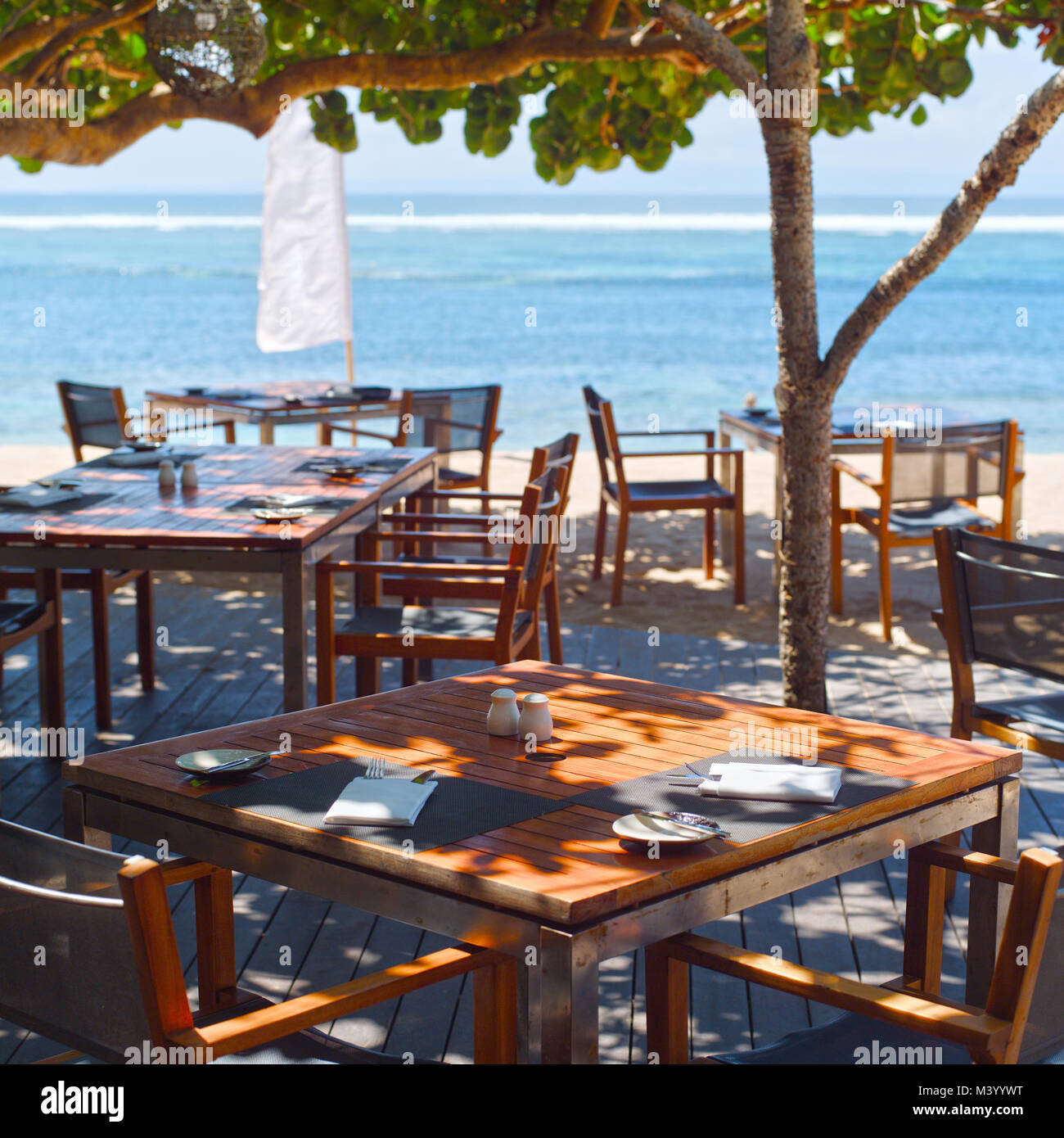 Wooden cafe table and chairs on a tropical beach in Bali with blue sea ...