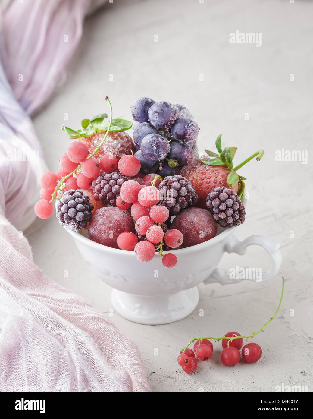 Assortment of frozen berries in white cup on the stone concrete ...