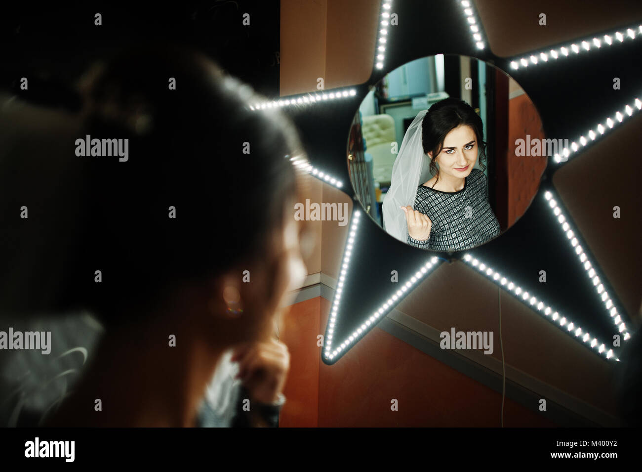 Fabulous bride looking at star-shaped mirror in makeup salon before the ...