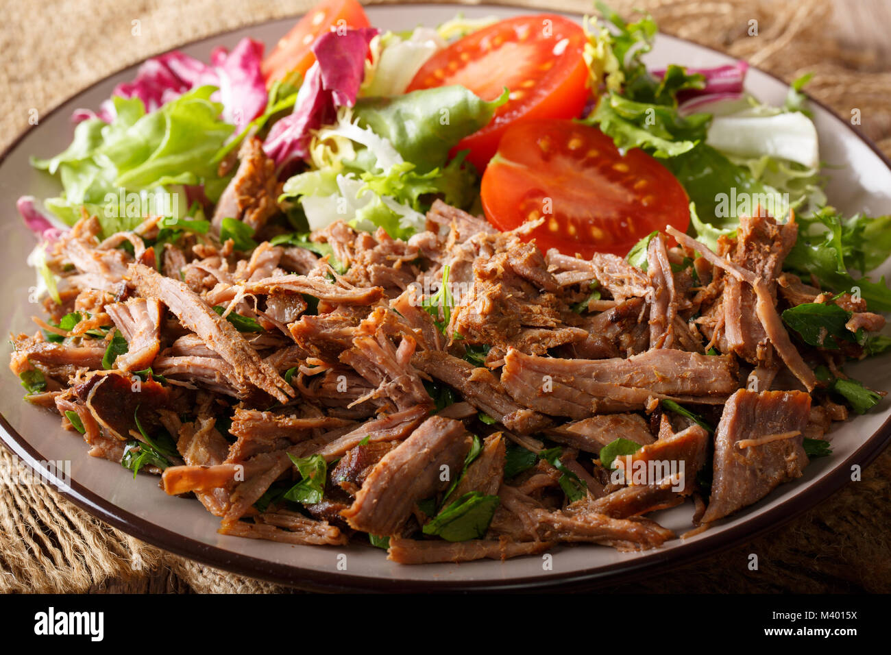 spicy pulled beef with fresh vegetable salad close-up on a plate ...