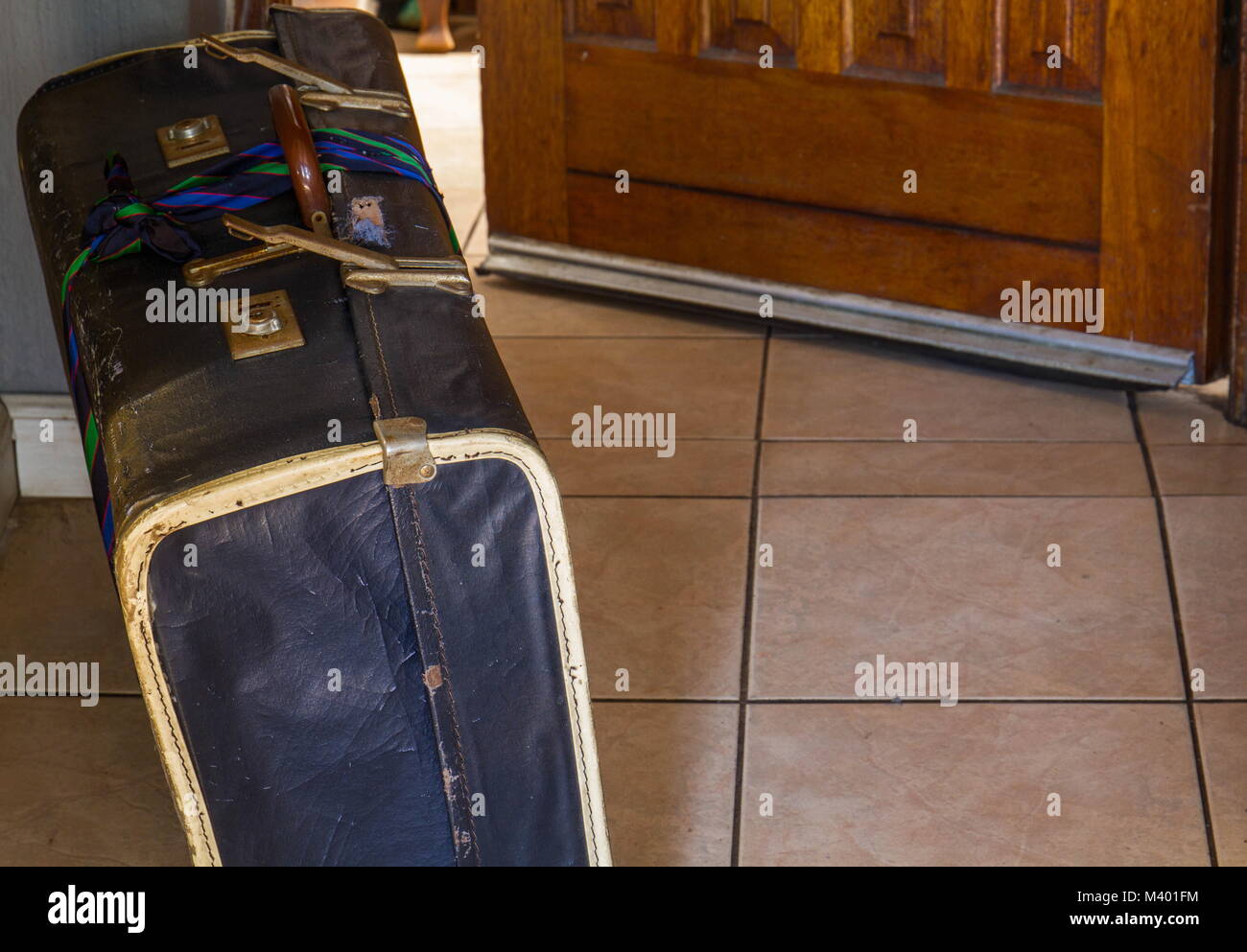 Dilapidated retro cardboard suitcase tied closed with a tie in front of ...