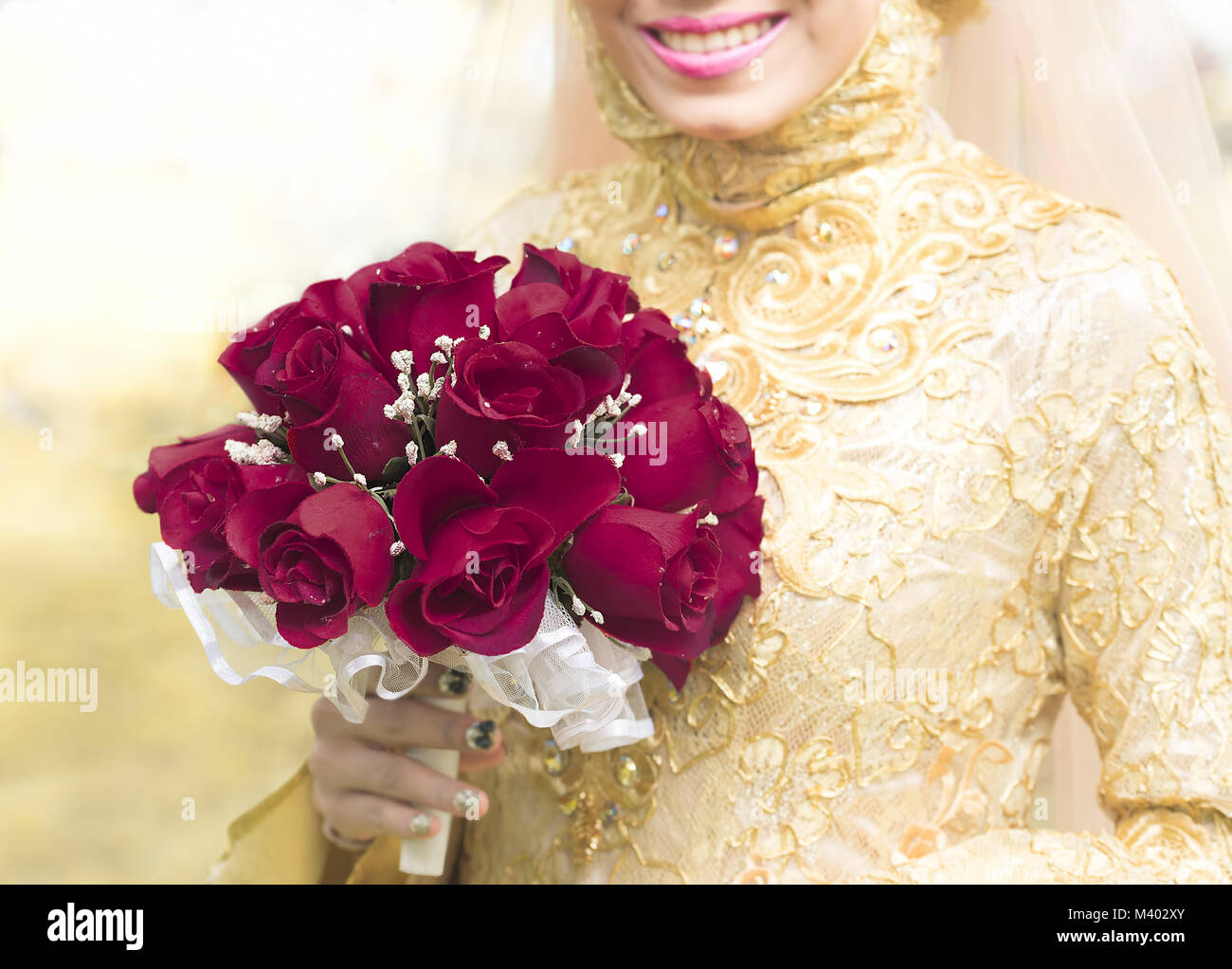 Muslim bride holding a wedding bouquet in her hand, a bunch of red ...