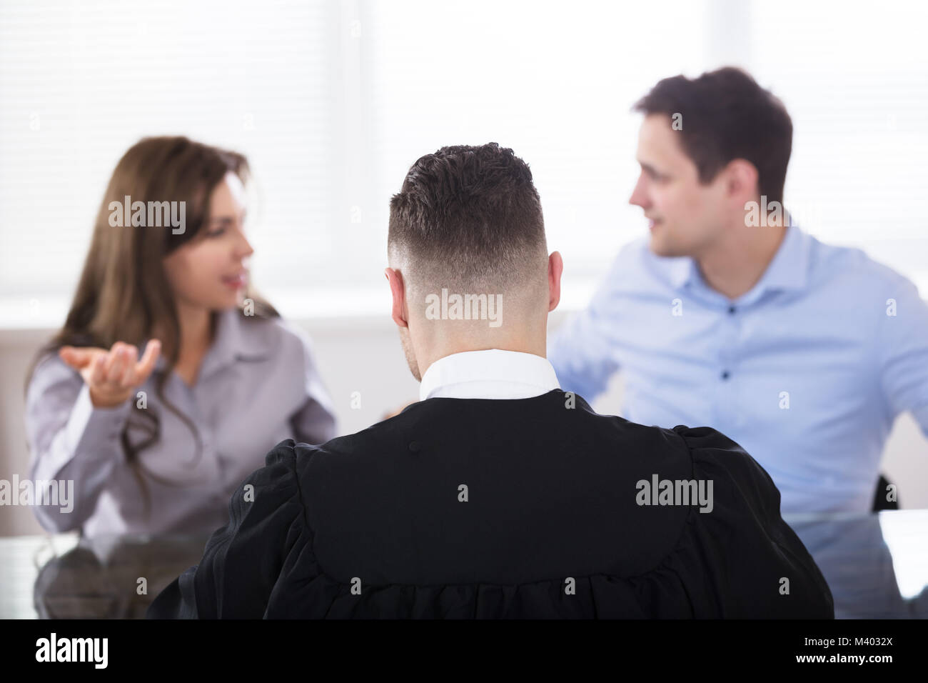 Rear View Of A Male Judge Sitting In Front Of Couple Quarreling Stock ...