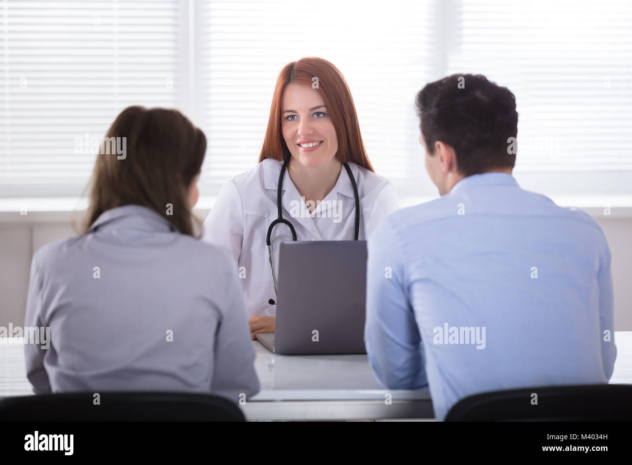 Rear View Of A Couple Sitting In Front Of Female Doctor Stock Photo - Alamy