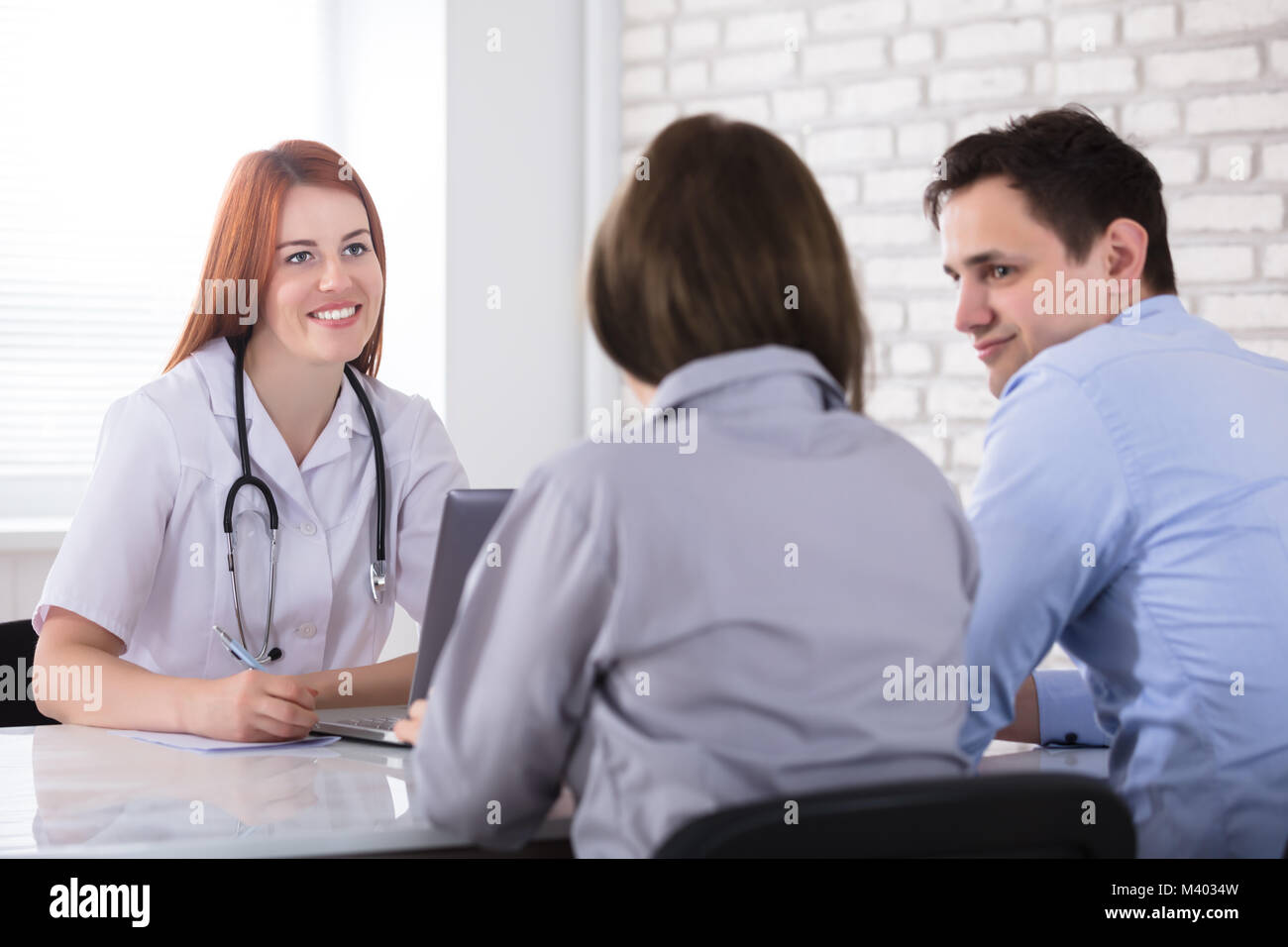 Rear View Of A Couple Sitting In Front Of Female Doctor Stock Photo - Alamy