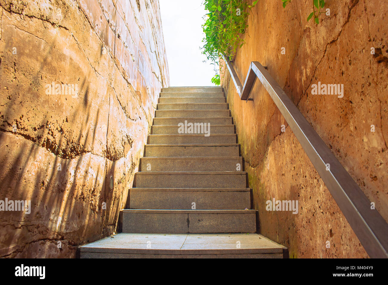 Empty concrete staircase and metal railing with brown clay wall that ...