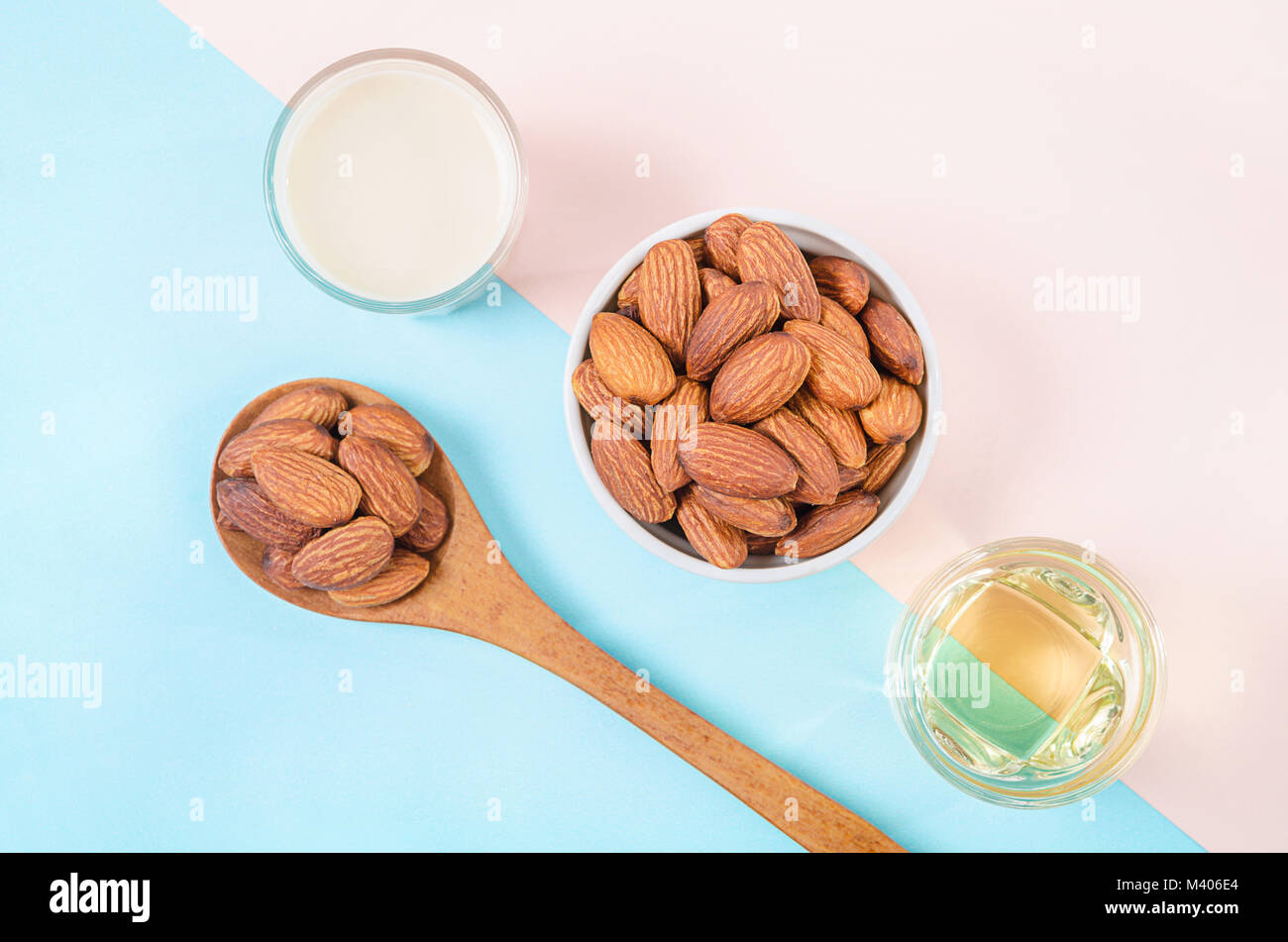 Peeled almonds with white bowl and cup of almond milk and oil on color ...