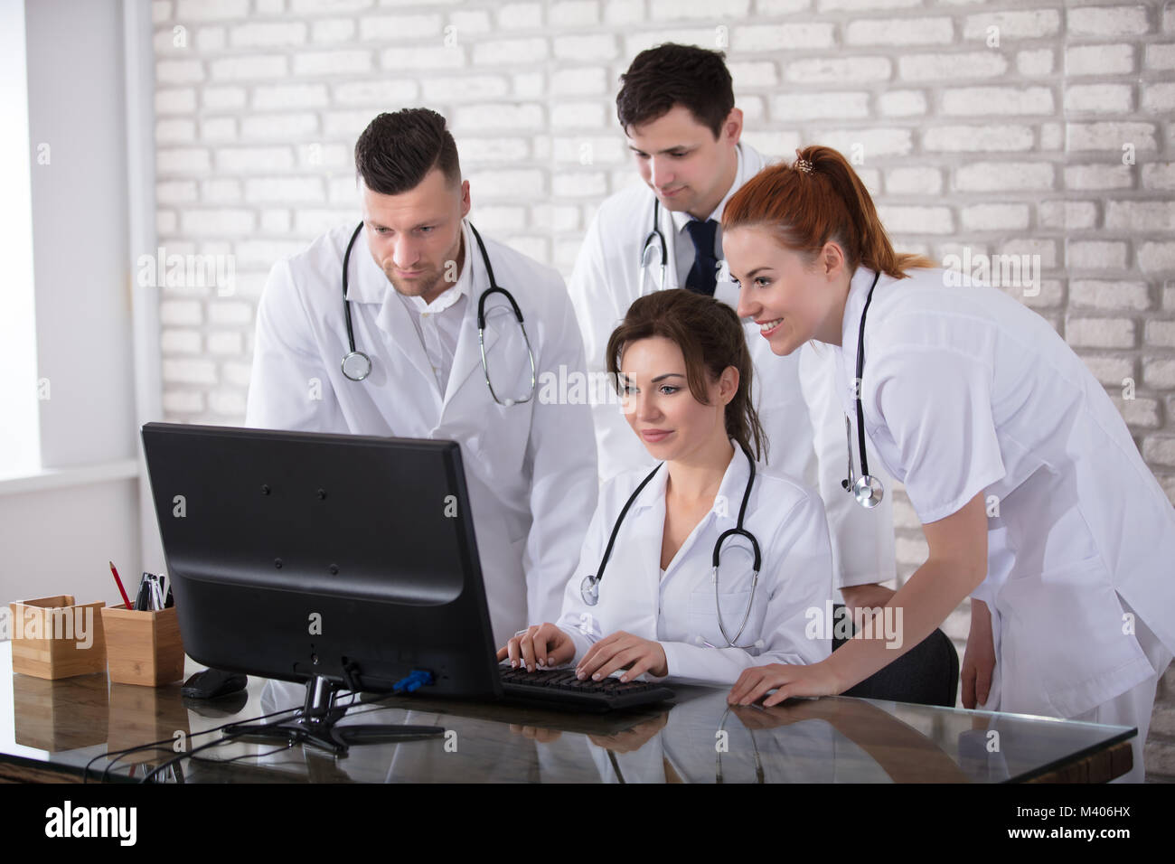 Group Of Smiling Doctors Looking At Computer In Clinic Stock Photo - Alamy