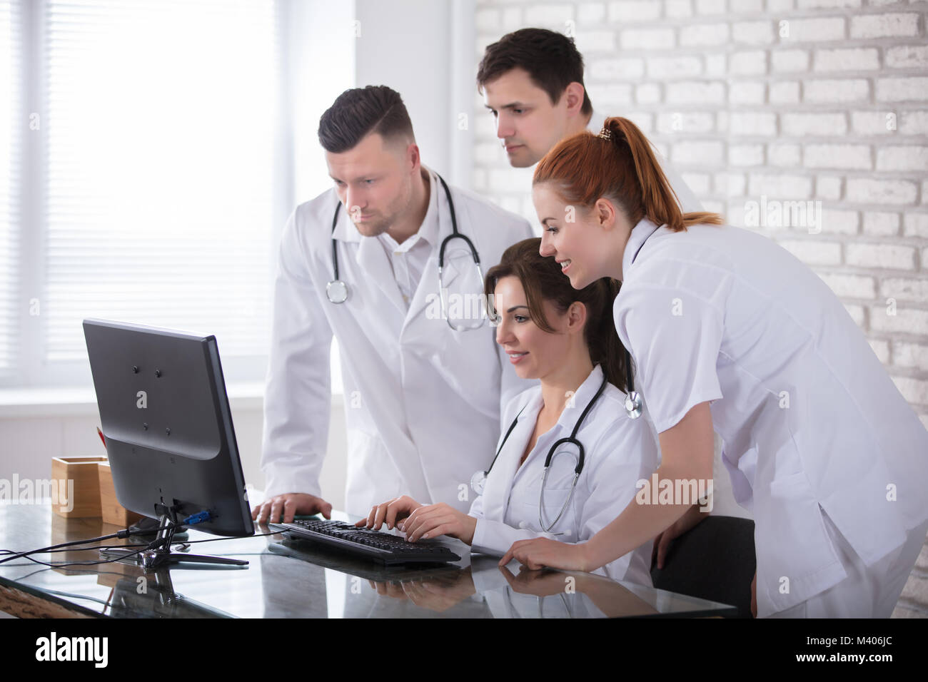 Group Of Smiling Doctors Looking At Computer In Clinic Stock Photo - Alamy