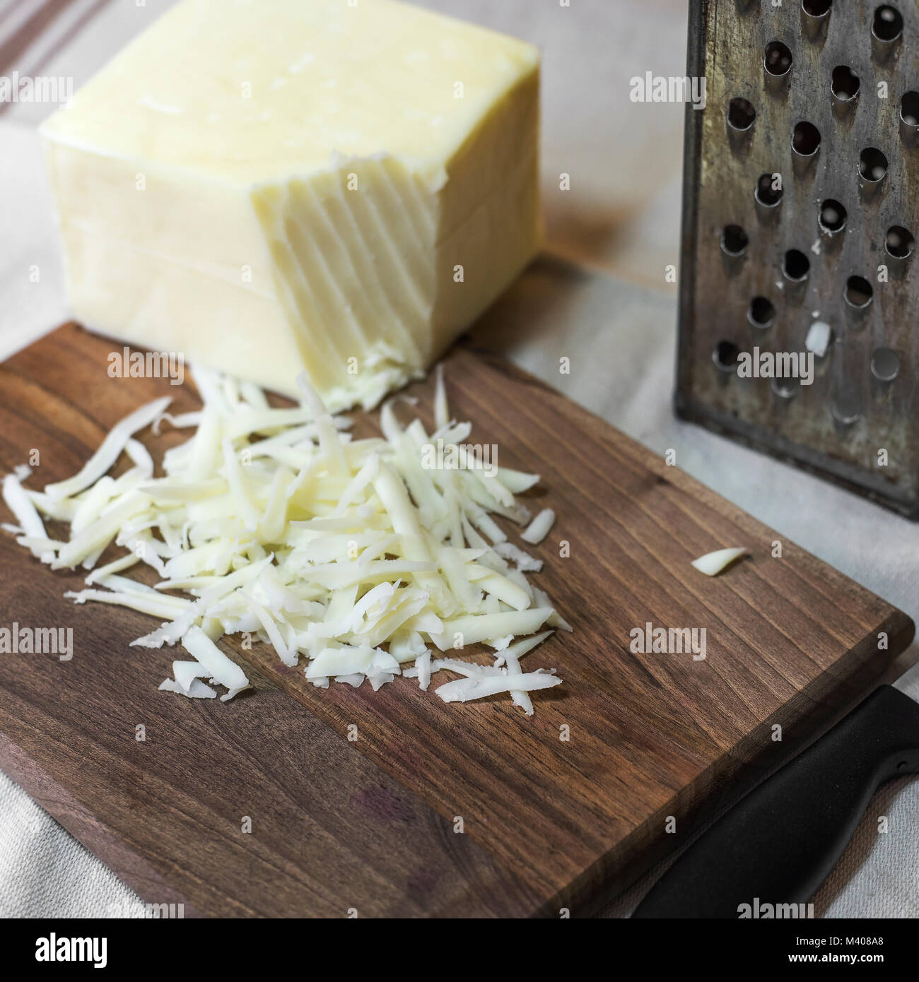 Grated cheese with grater and knife, close up Stock Photo - Alamy