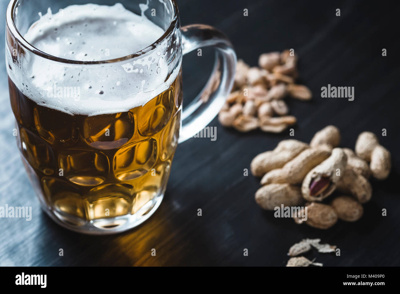 Glass of beer and peanuts on the dark wooden background Stock Photo - Alamy
