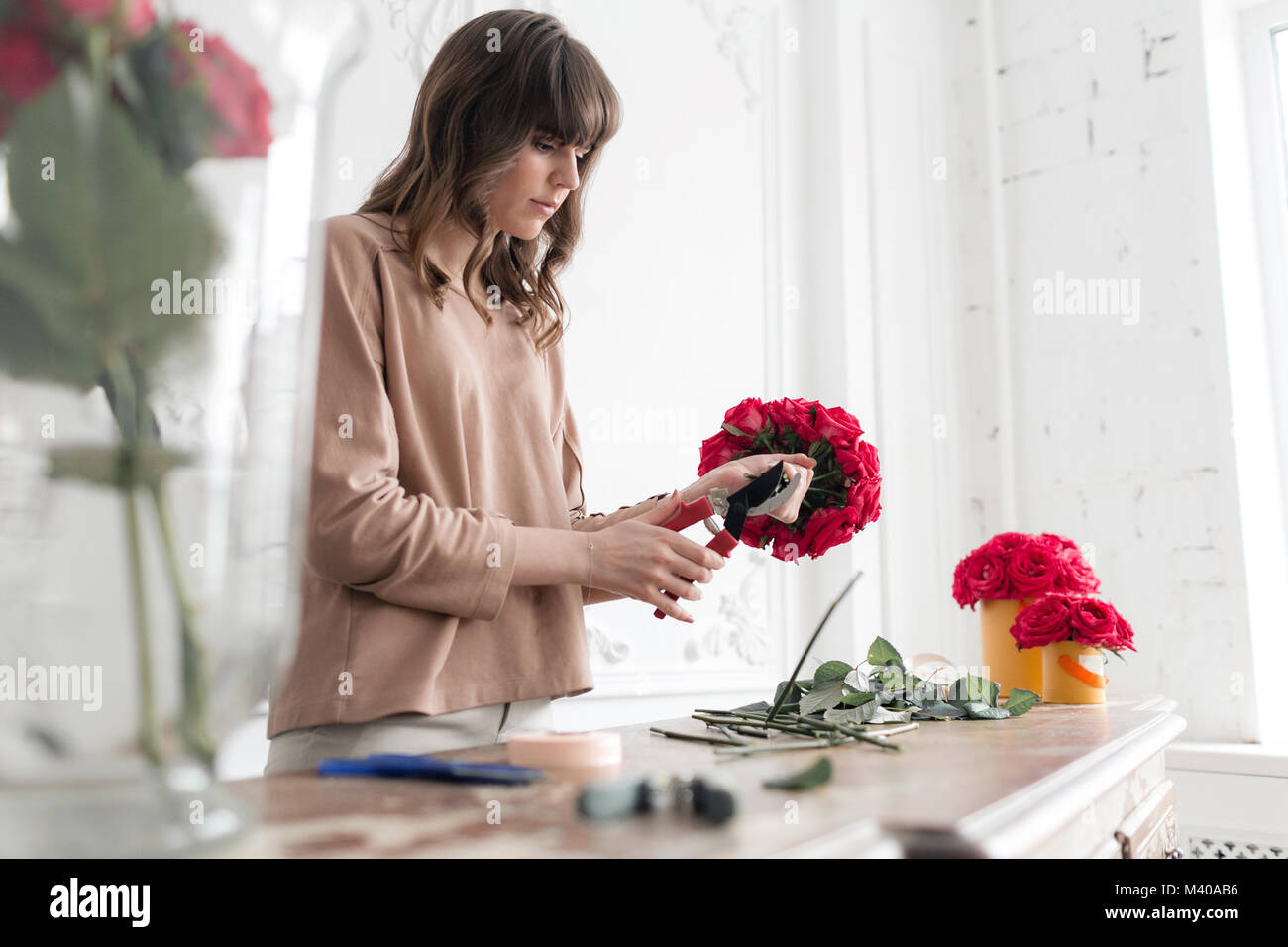 Young woman florist arranging plants in flower shop. People, business ...
