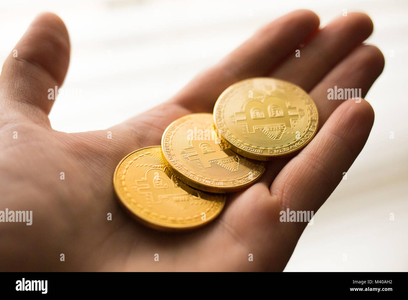Three bitcoin coins in a hand close up gold Stock Photo - Alamy