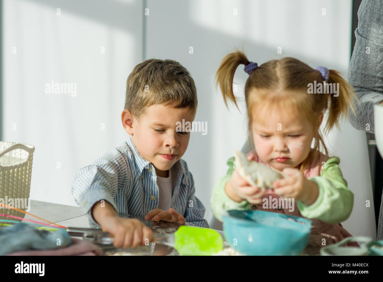 Two small children prepare something from the dough. A boy and a girl ...