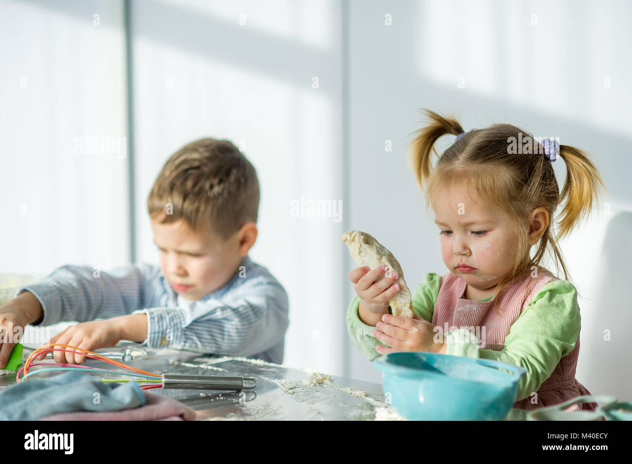 Two small children prepare something from the dough. A boy and a girl ...
