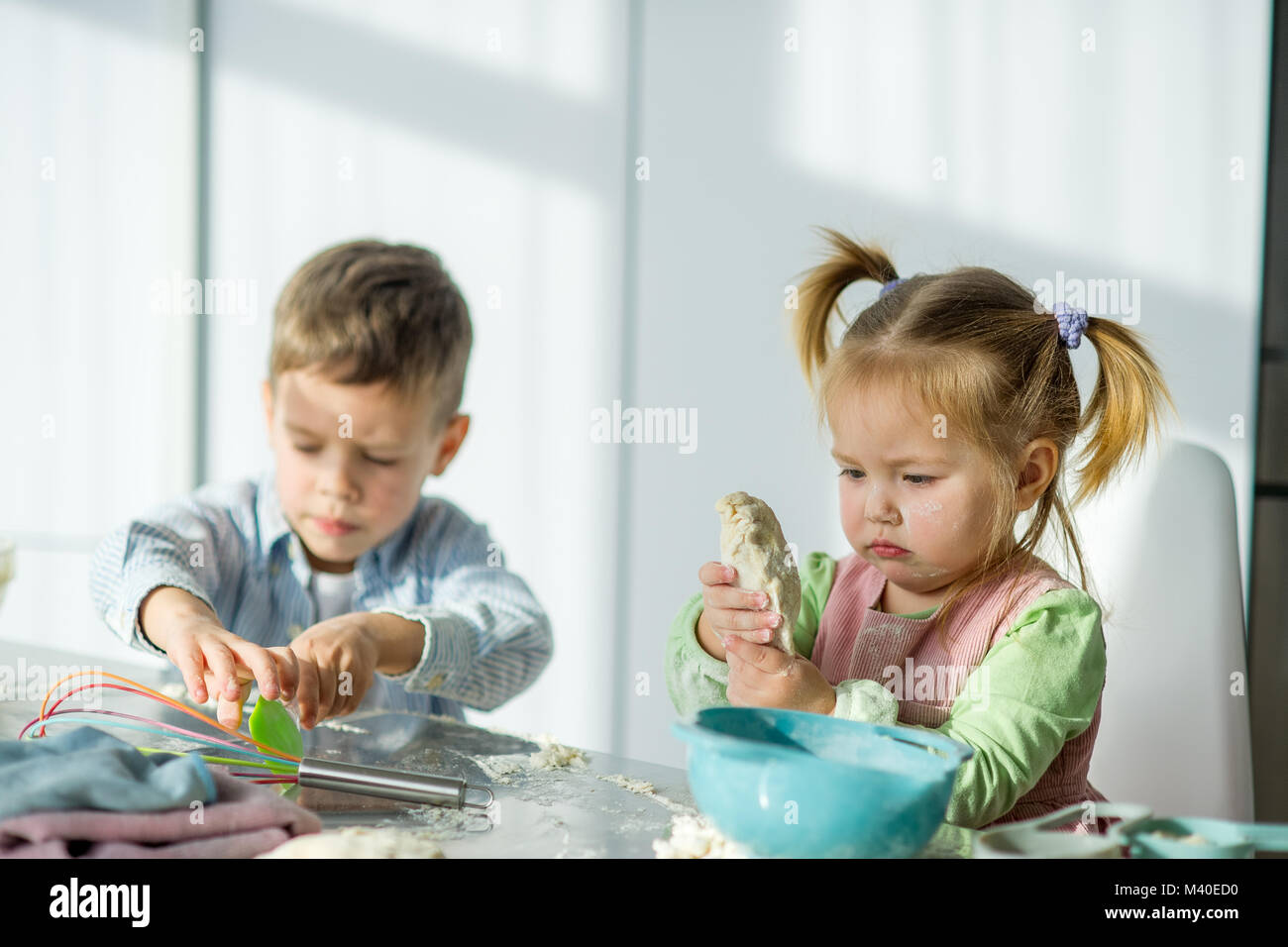 Two small children prepare something from the dough. A boy and a girl ...