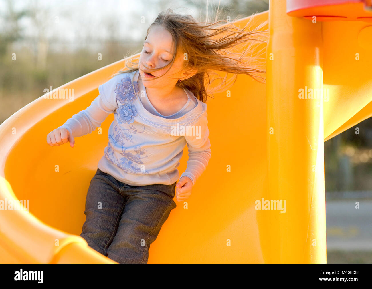 A young girl sliding down a yellow, spiral sliding board Stock Photo ...
